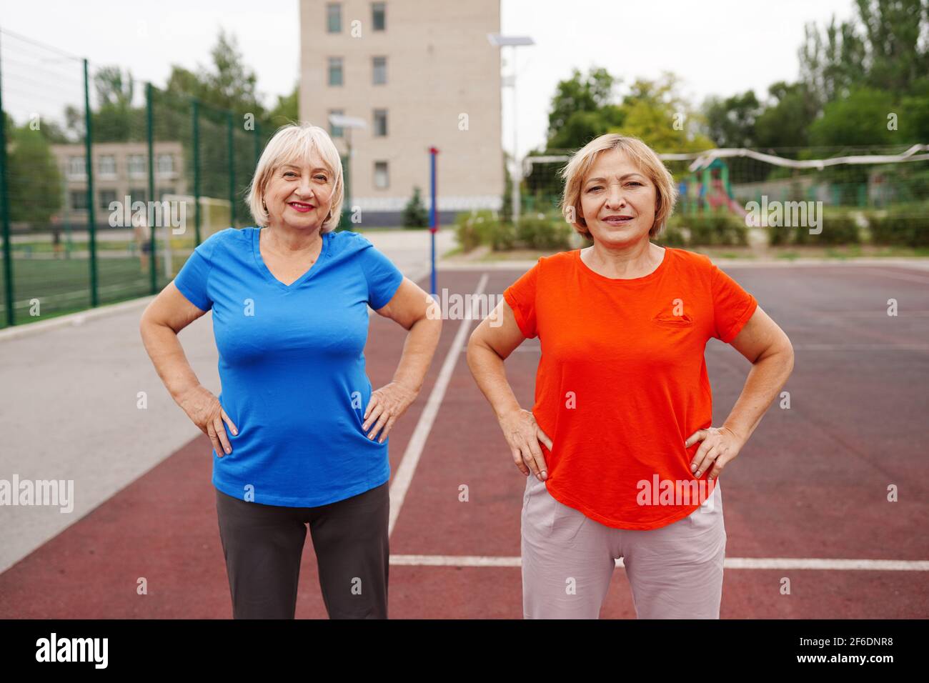 two adult women 58 and 64 years old doing exercises outdoors on the ...