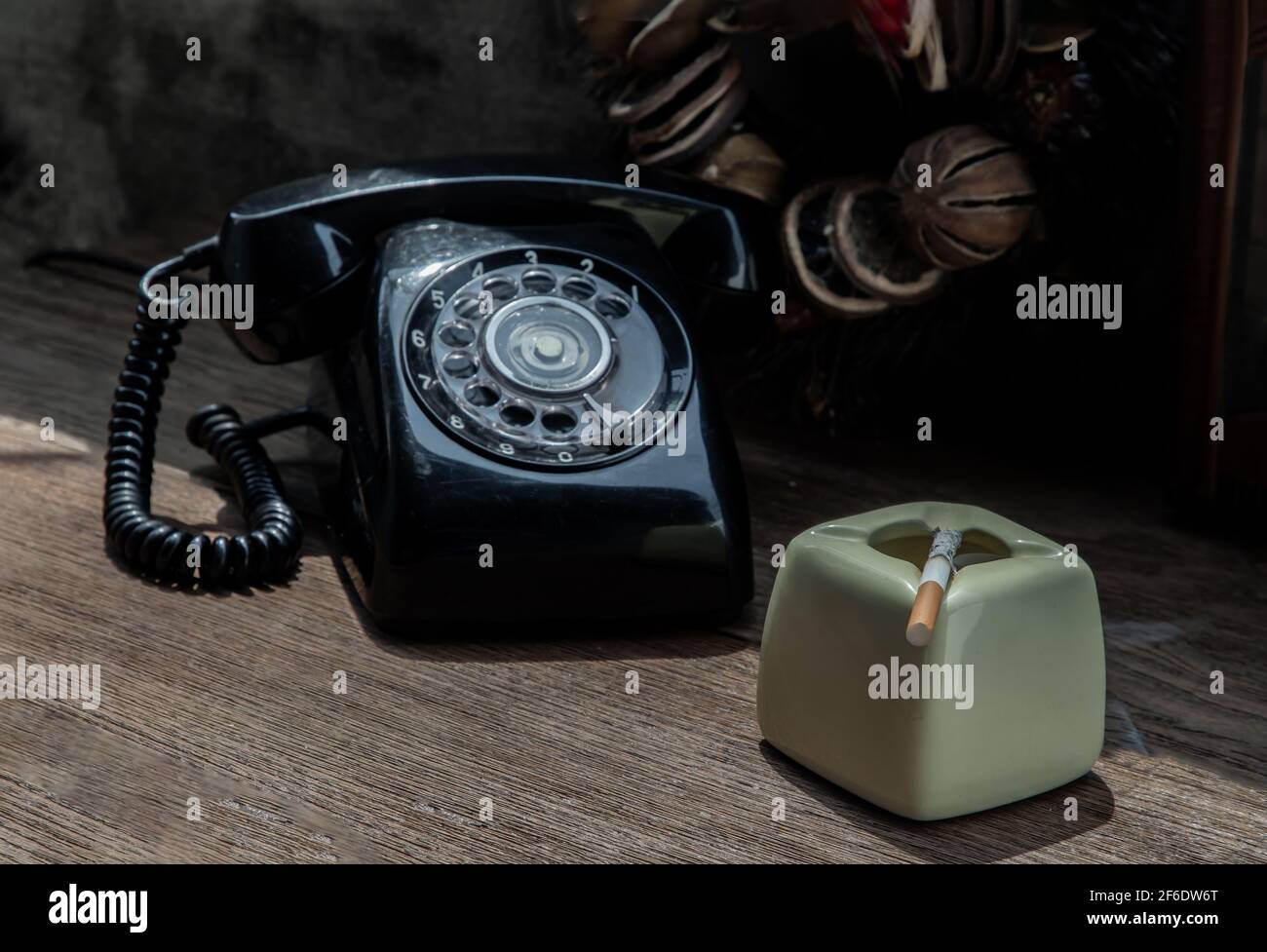 A litted cigarette on greyish green ashtray which is placed next to old ...