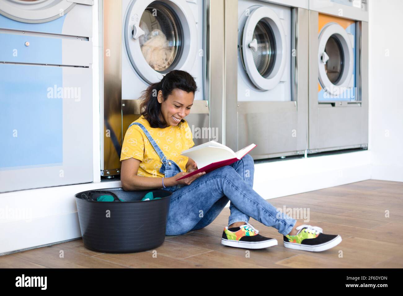 Latin woman reading a book sitting on the floor while waiting for ...