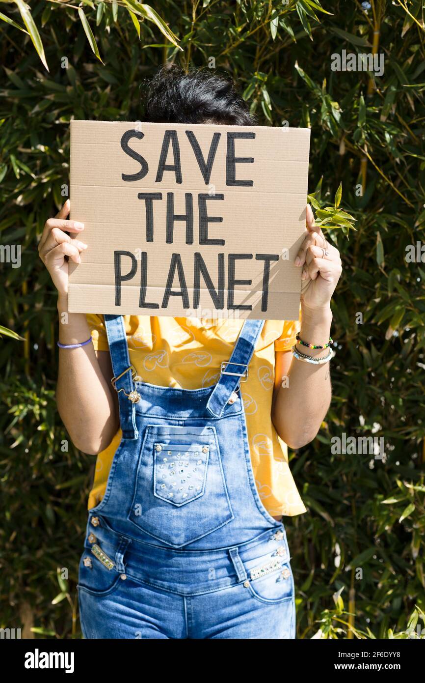 Portrait of woman covering her face with a banner with the slogan Save ...