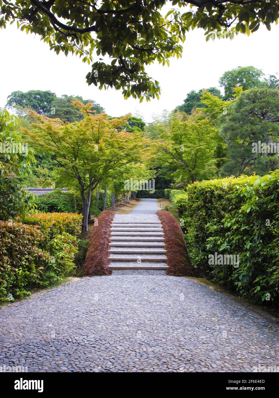 The view of the gardens with curved, arched walkway bridge on a grey ...