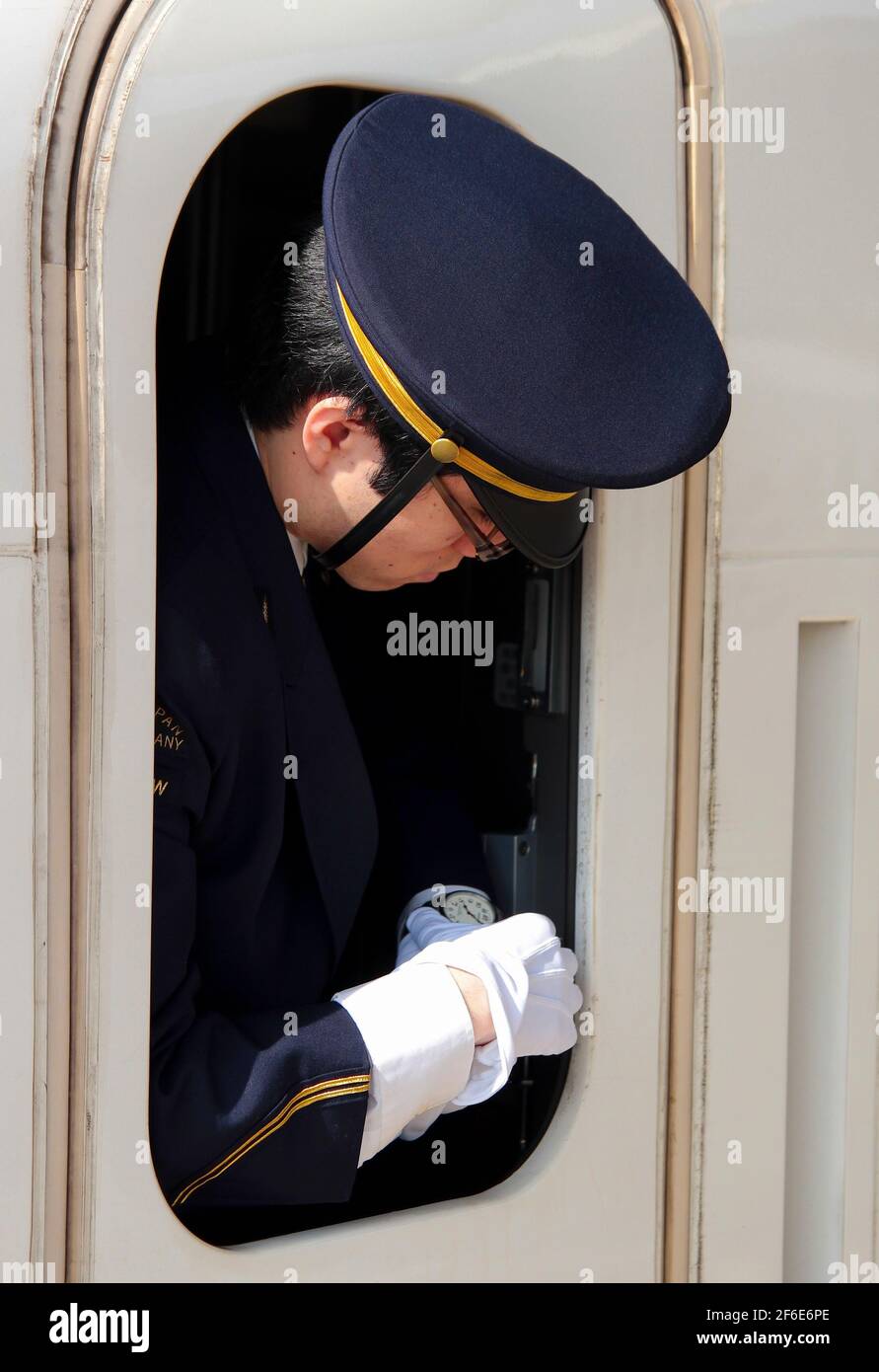 A uniformed conductor on a Shinkansen train checks his watch to stay on ...