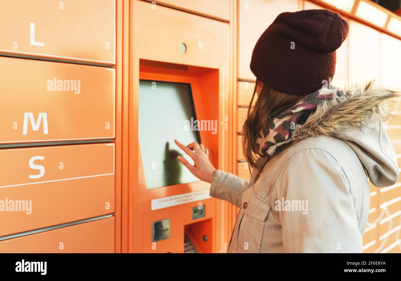 Woman picks up mail from automated self-service post terminal machine ...