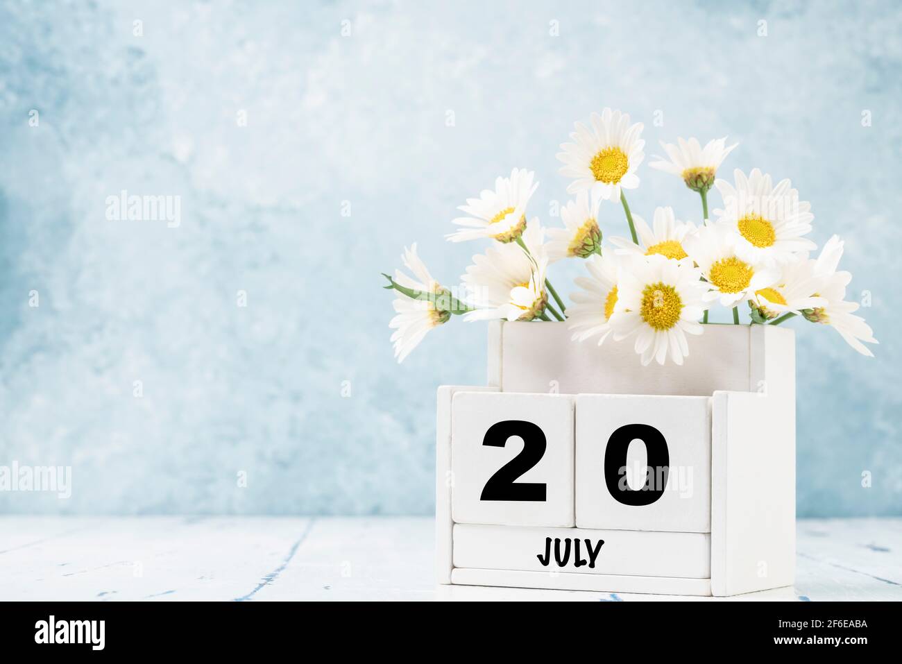 White cube calendar for July decorated with daisy flowers over blue ...