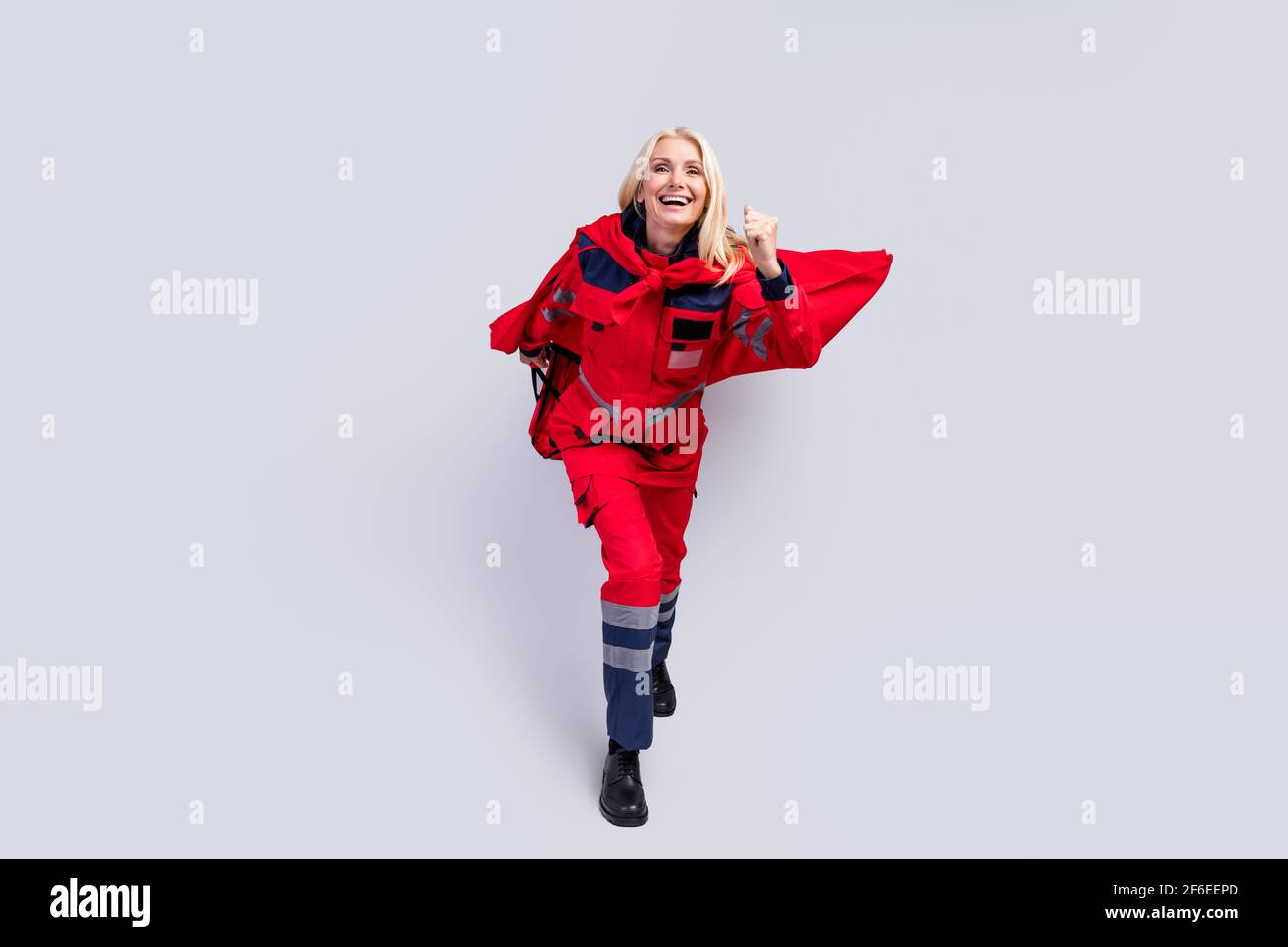 Full length photo of happy old paramedic woman wear red cape uniform ...
