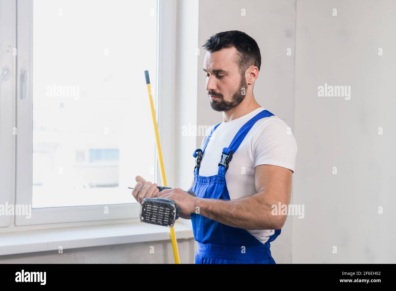 A foreman in a blue overalls holds a tape measure in his hand Stock ...