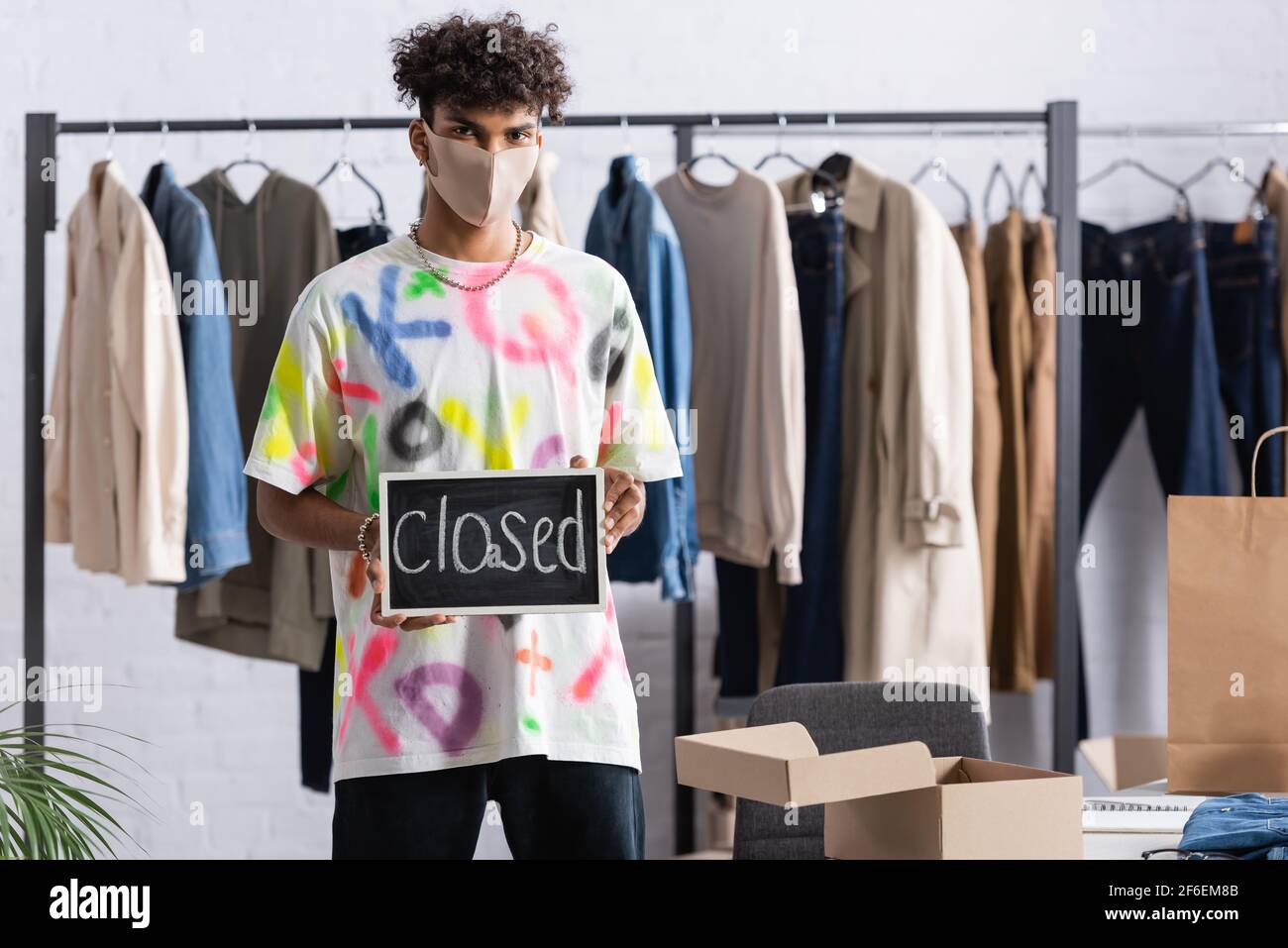 Stylish african american owner of showroom holding chalkboard with ...
