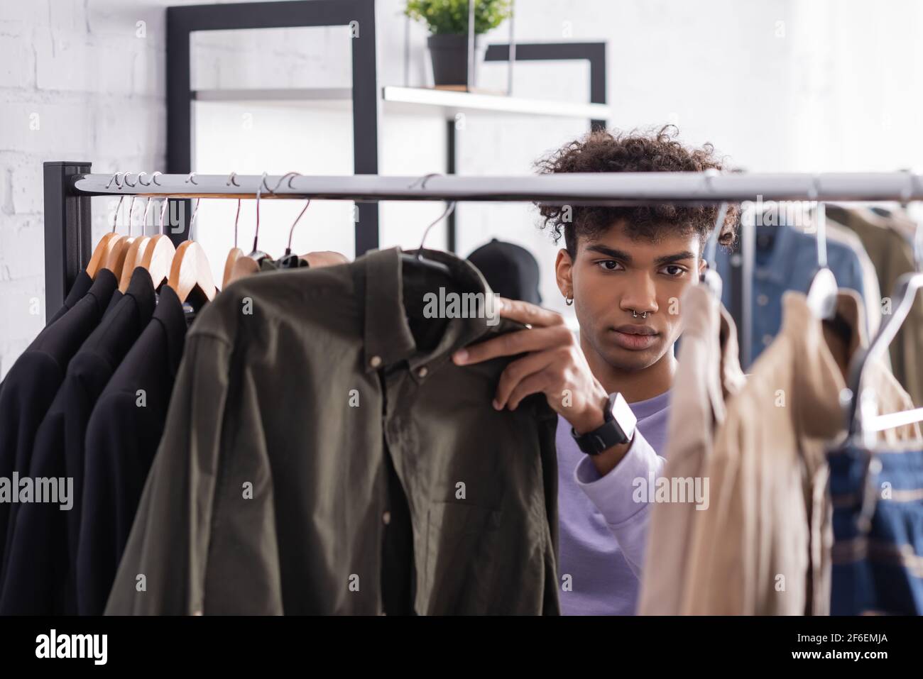 African american showroom owner working with clothes on hanging rack on ...