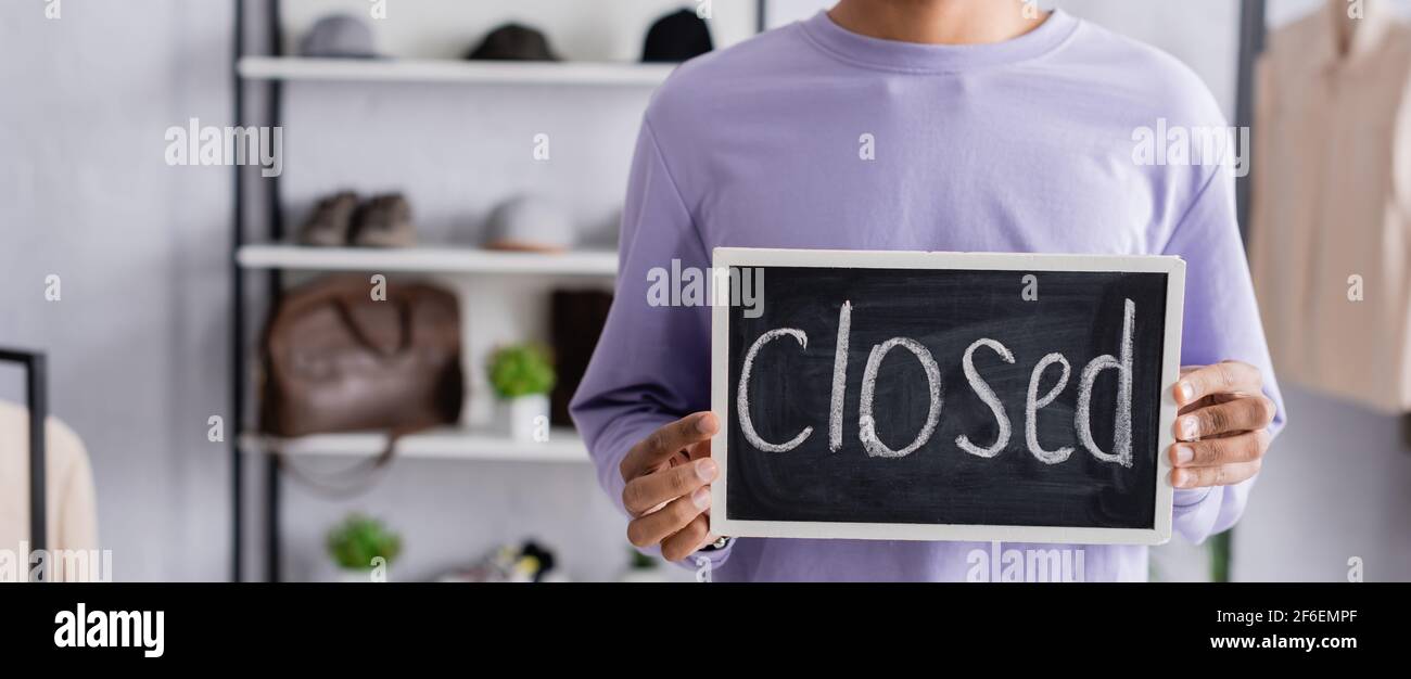 Cropped view of african american owner of showroom holding chalkboard ...