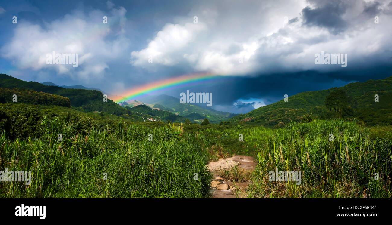 Panoramic colourful rainbow over a mountain valley on a rainy day ...