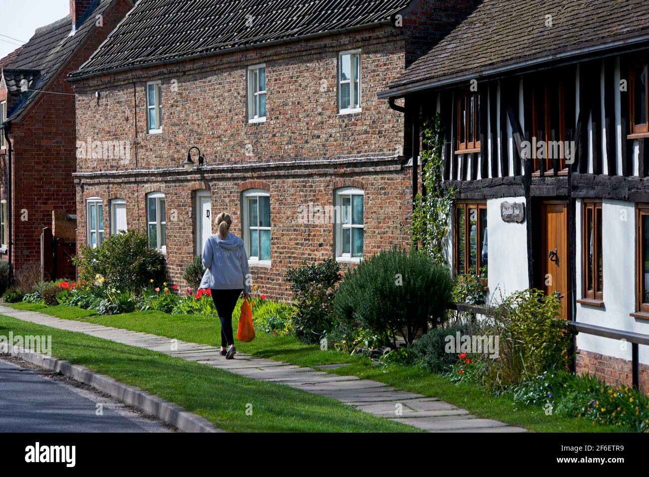 Young woman walking past cottages in the village of Wheldrake, North ...