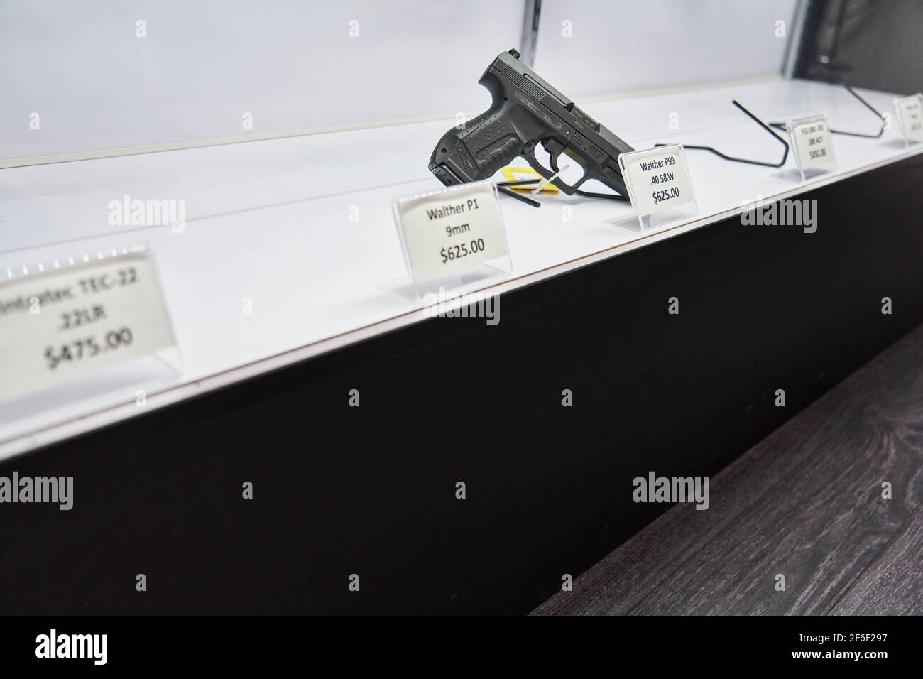 Handguns with labels and price tags on sale on shelves at gun store ...