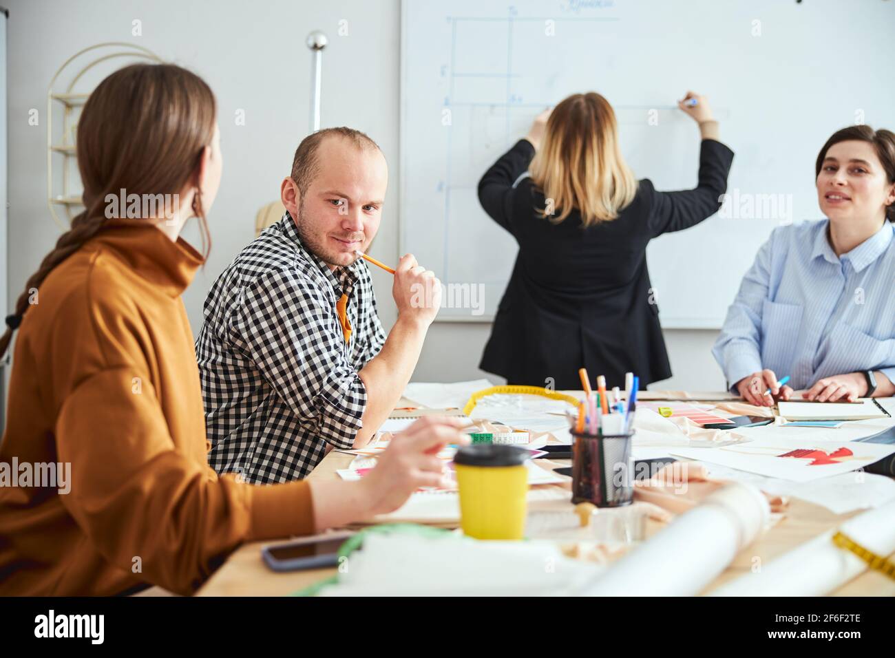 Designers waiting for the colleague to finish drawing on the board ...