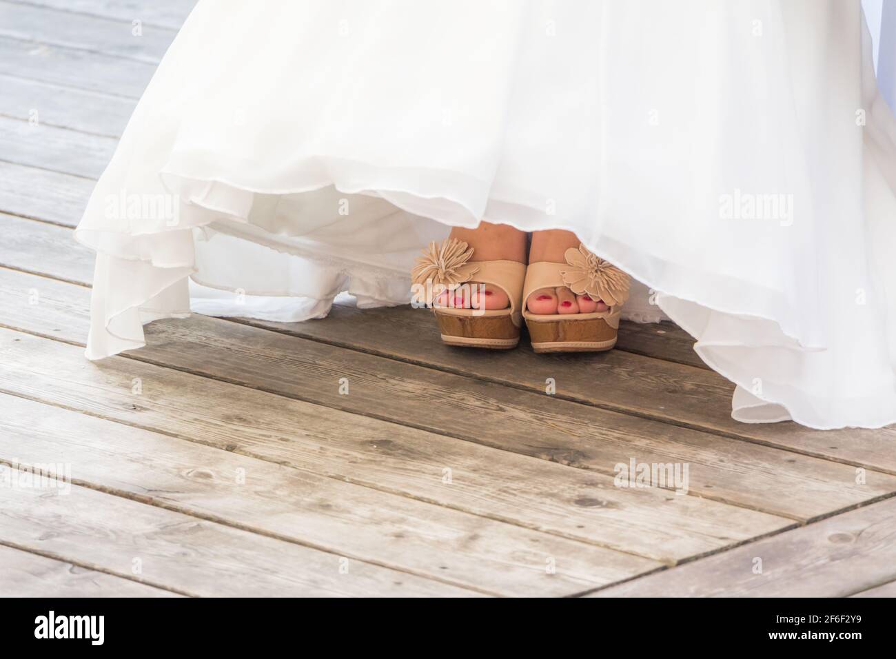 Wedding bride shoes and feet under white bridal gown tulle. The woman ...