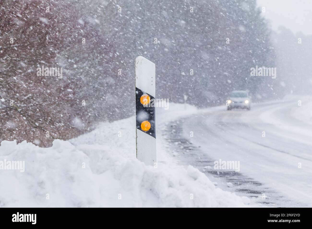 Reflector post at snowy white snow blizzard car winter road. The street ...
