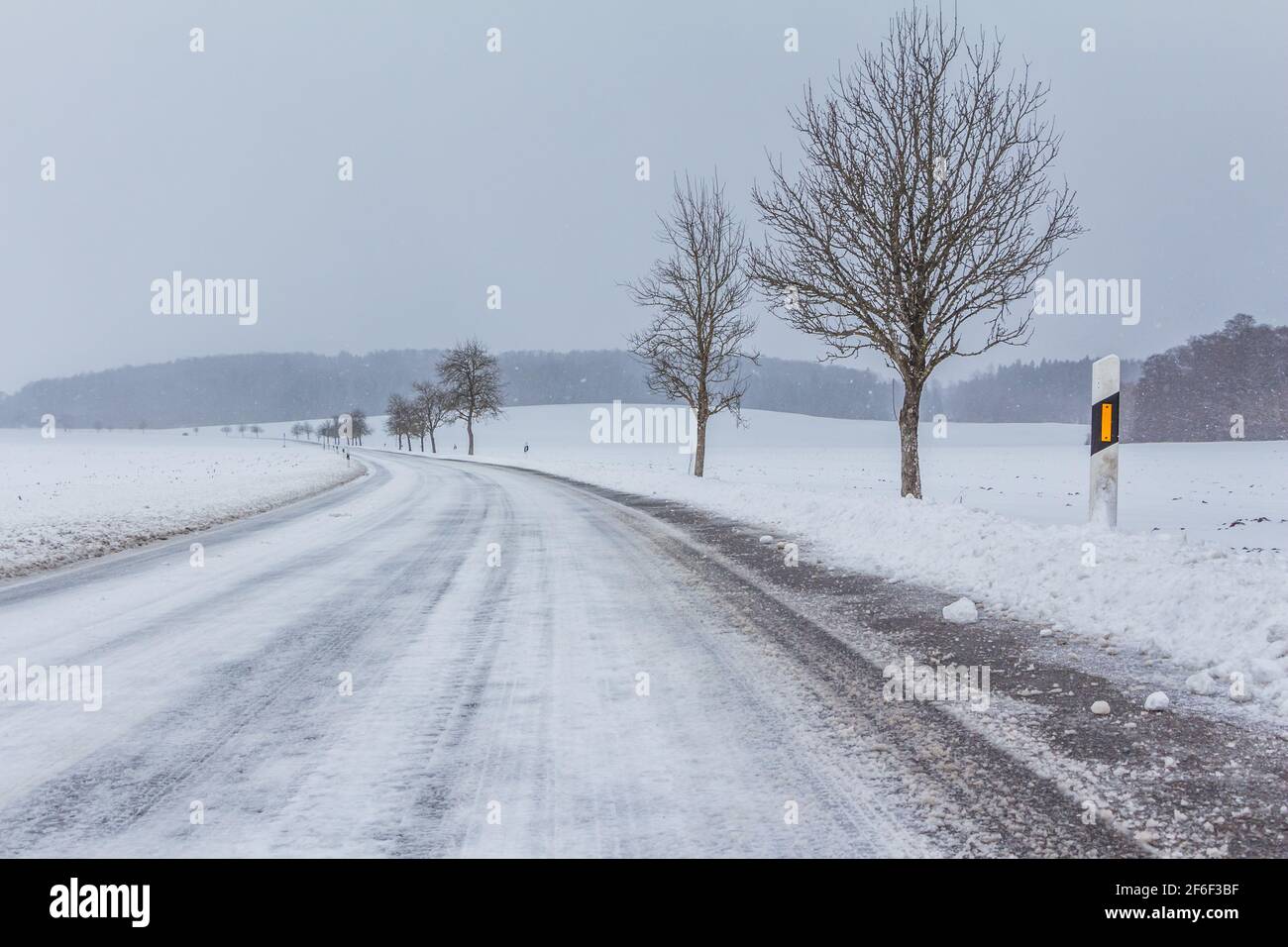 Empty snowy icy winter road with white snowy track. The street track is ...