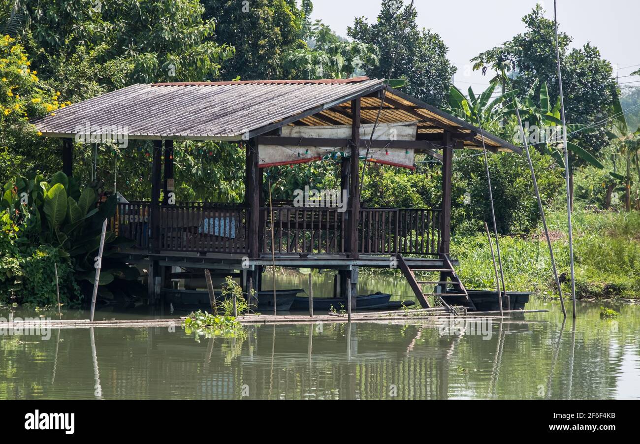 The old wooden pavilion with a small boat below near the small river in ...