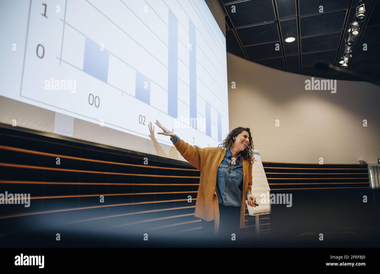 businesswoman gesturing at projection screen and making a presentation ...