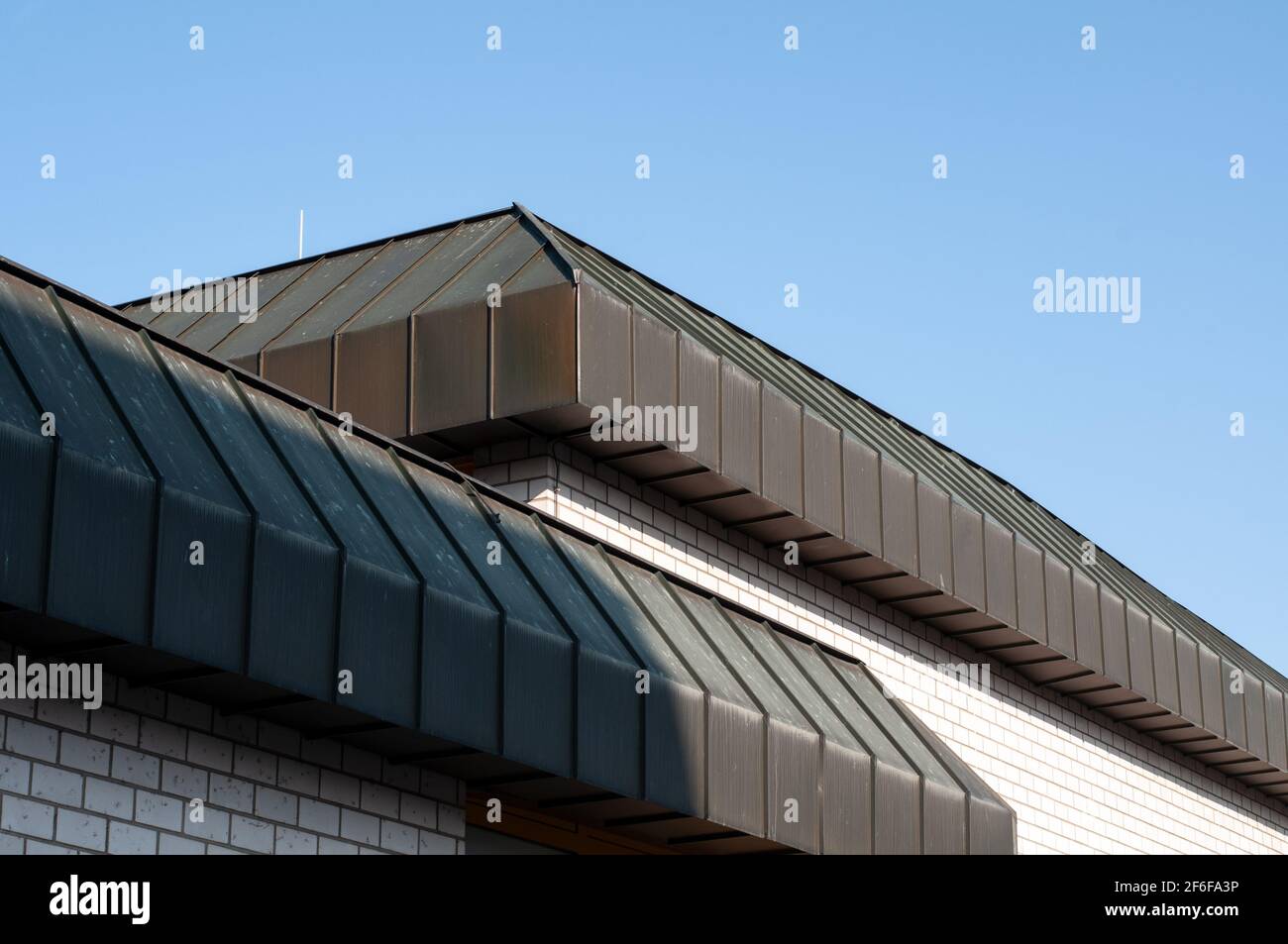 a modern building with brick facade and roofs covered with copper ...