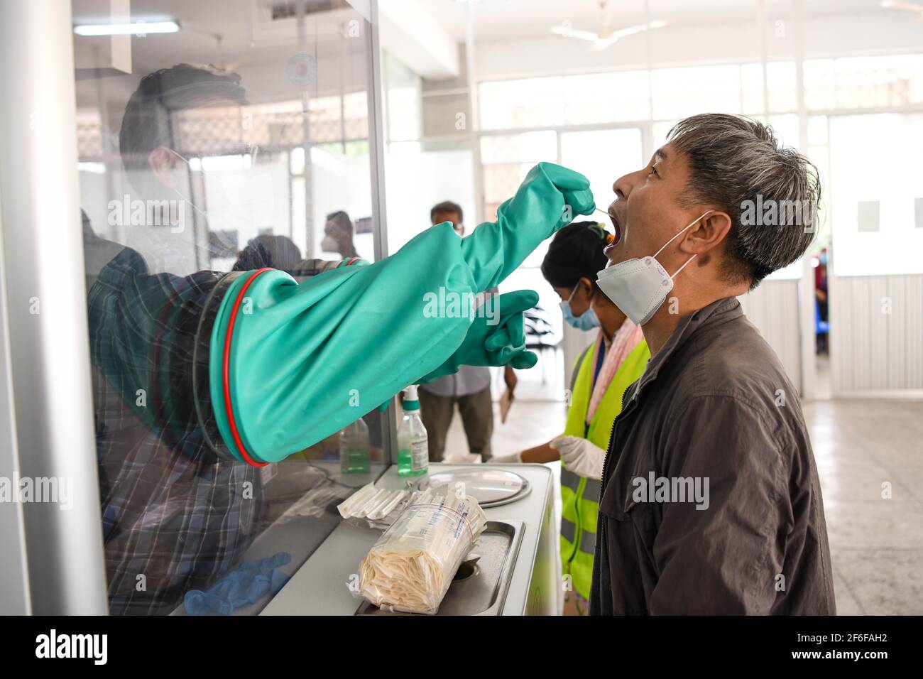 A health worker collects a swab sample from a foreigner to test for the ...