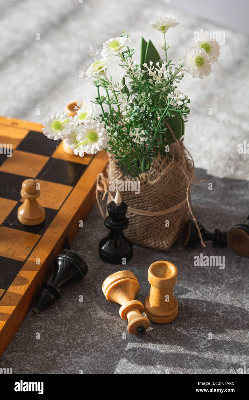 Chess. Chess board, chess pieces and flowers on a gray-blue background ...