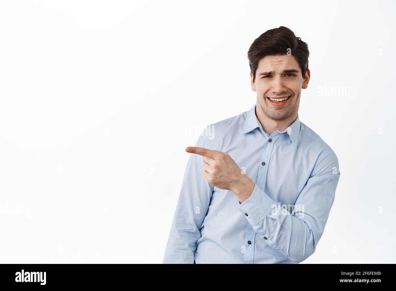Cool and handsome young man in office clothes, pointing aside at promo ...