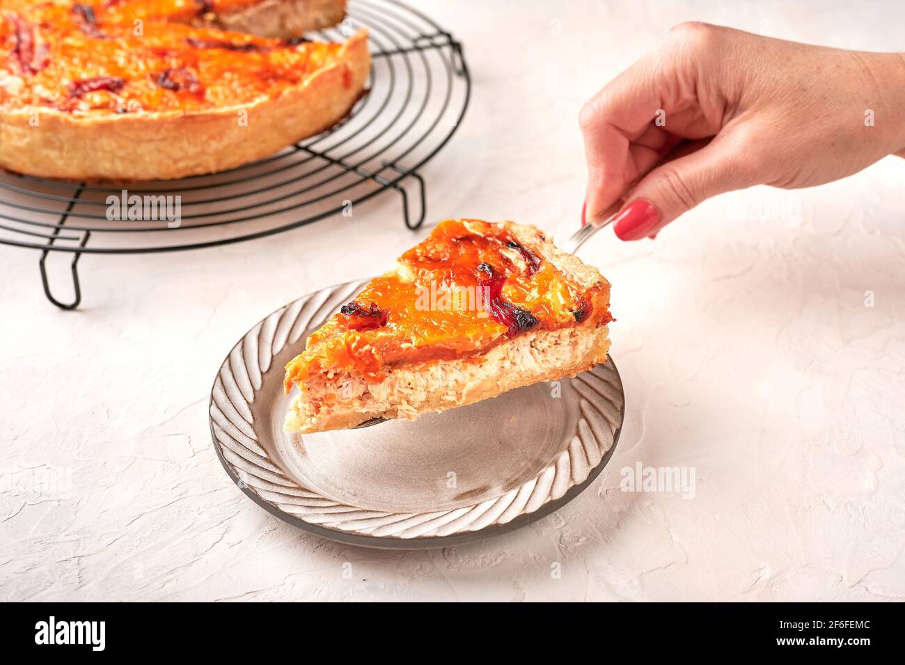 Woman's hand holds on a shoulder blade piece of homemade quiche pie ...
