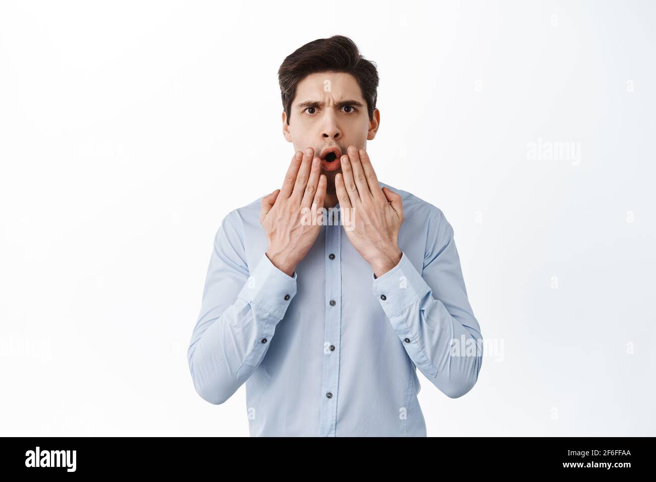 Man looks shocked and startled by someone, hold hands near mouth and ...