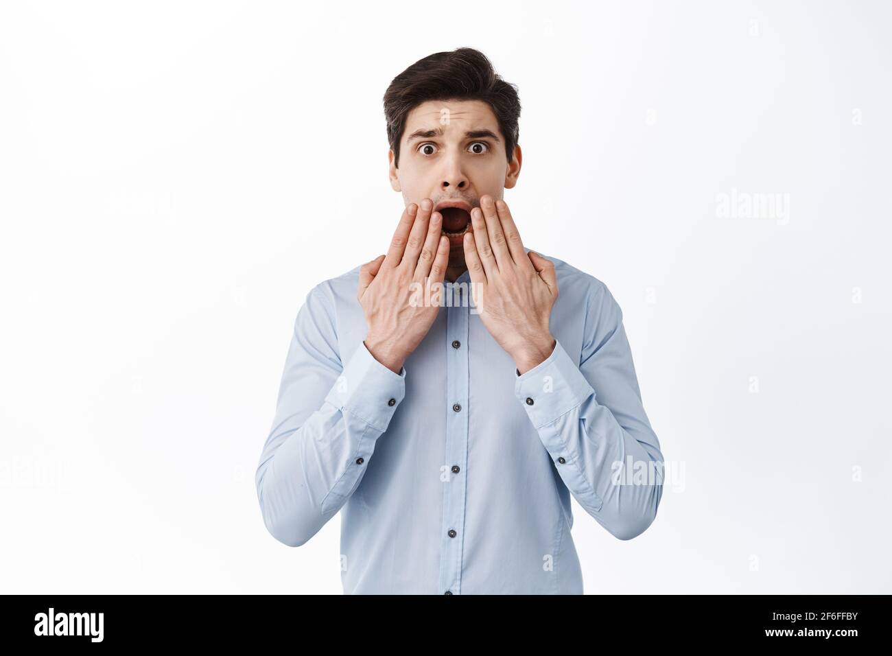 Anxious man screaming, look i panic, holding hands near mouth and stare ...