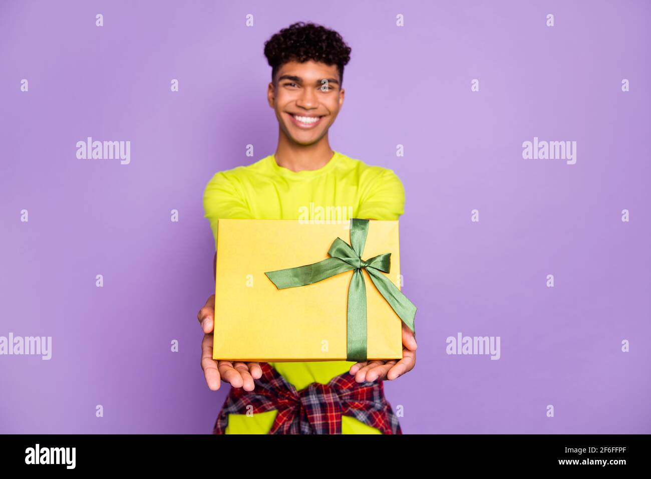 Photo portrait of young curly guy holding present box with ribbon ...