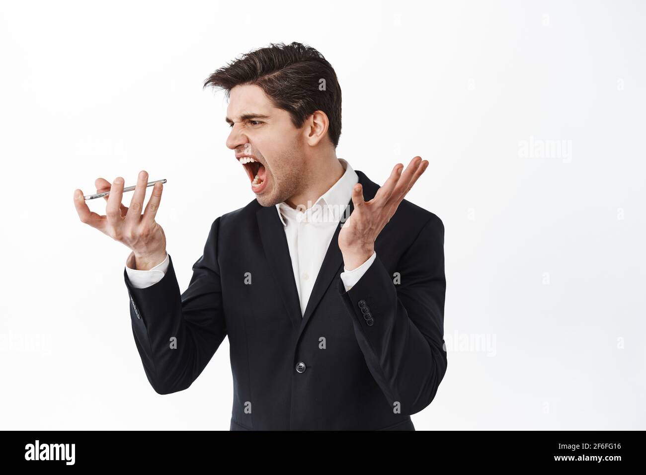 Angry boss, entrepreneur in suit screaming at smartphone, shaking hands ...