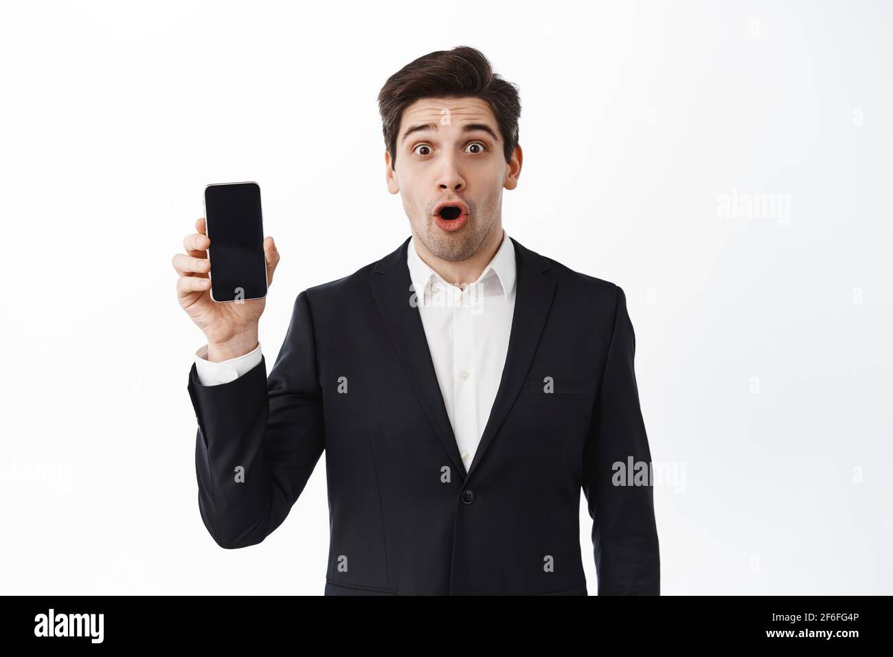 Surprised business manager in suit showing empty phone screen, make wow ...