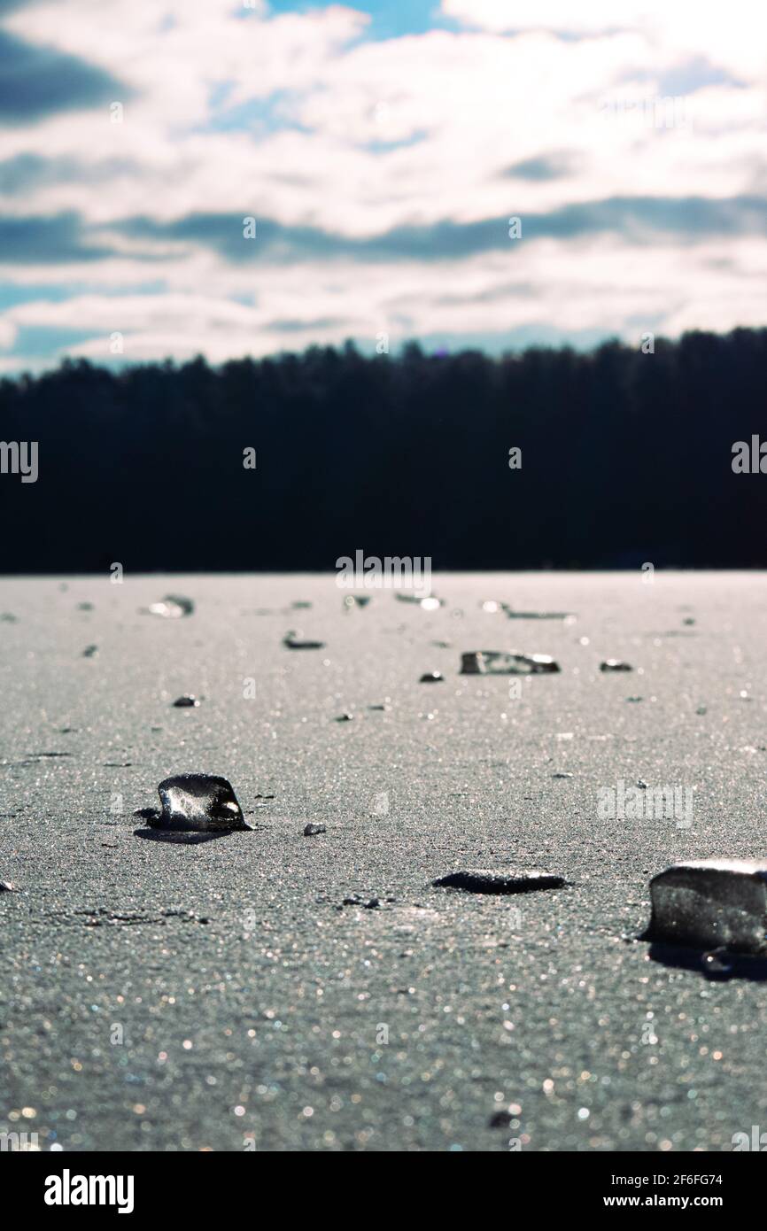 Large chunks of ice covering a frozen lake under a blue cloudy sky. The ...