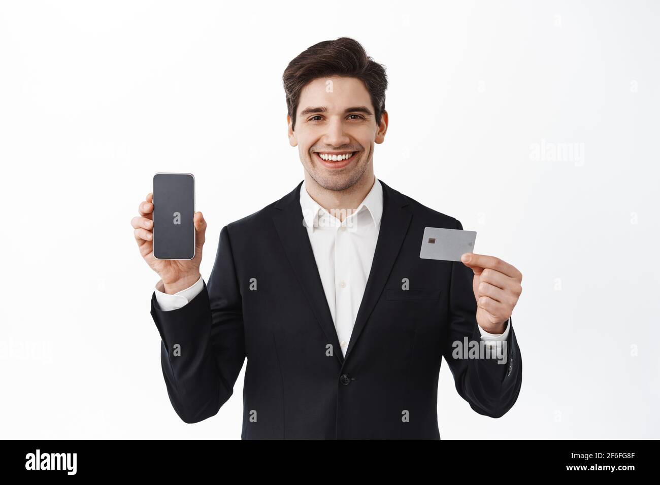 Handsome bank clerk showing smartphone screen and plastic credit card ...