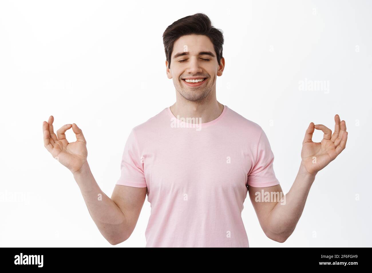 Smiling relaxed man meditating, holding hands in zen om gesture, feel ...