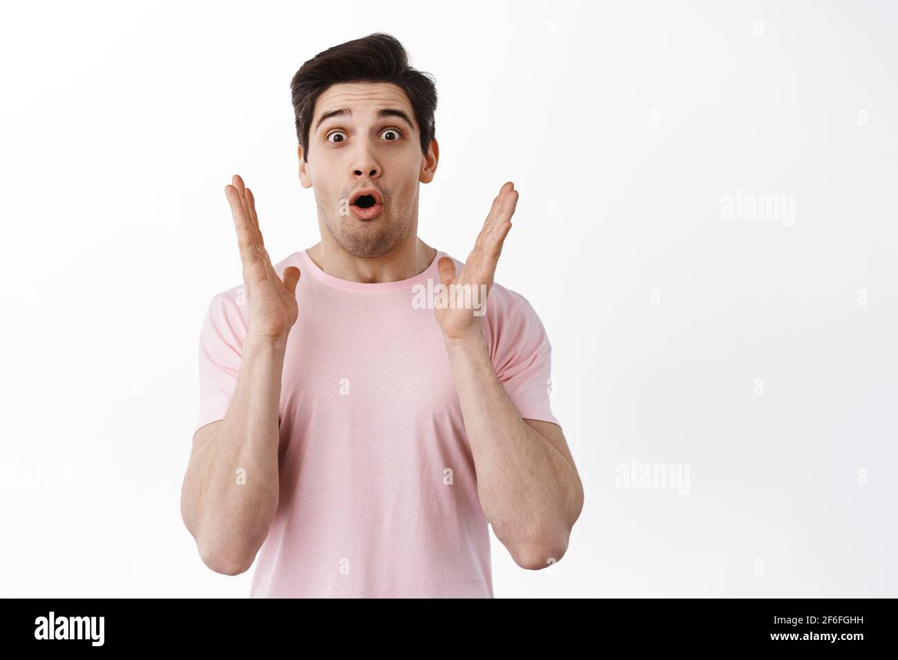 Surprised handsome man hear amazing news, clap hands and say wow, stare ...