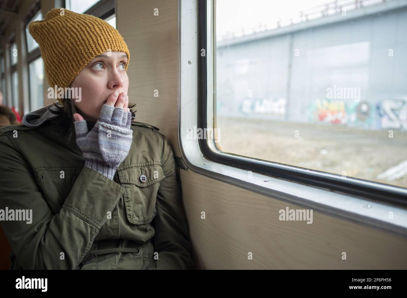 Frightened woman traveling in a train and looking out the window, she ...