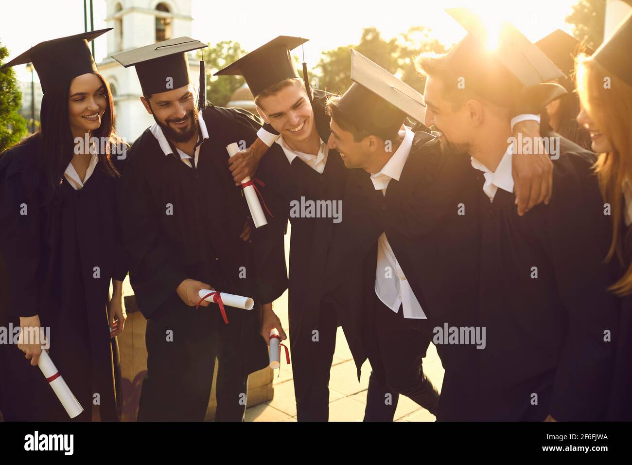 Happy and successful university graduates in academic gowns hold ...