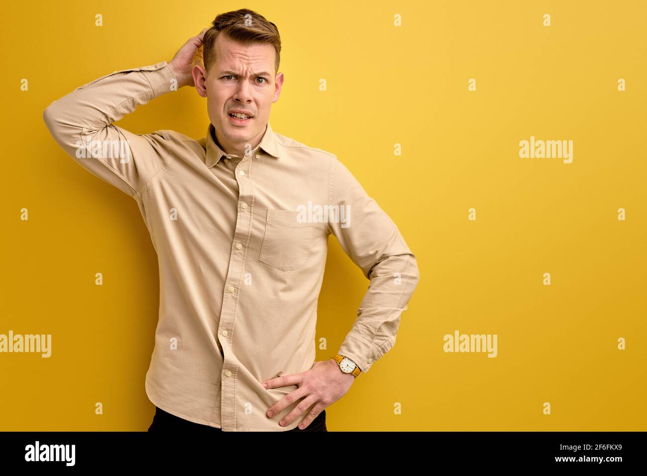 doubtful young guy stand thinking, scratch back of head thinking about ...