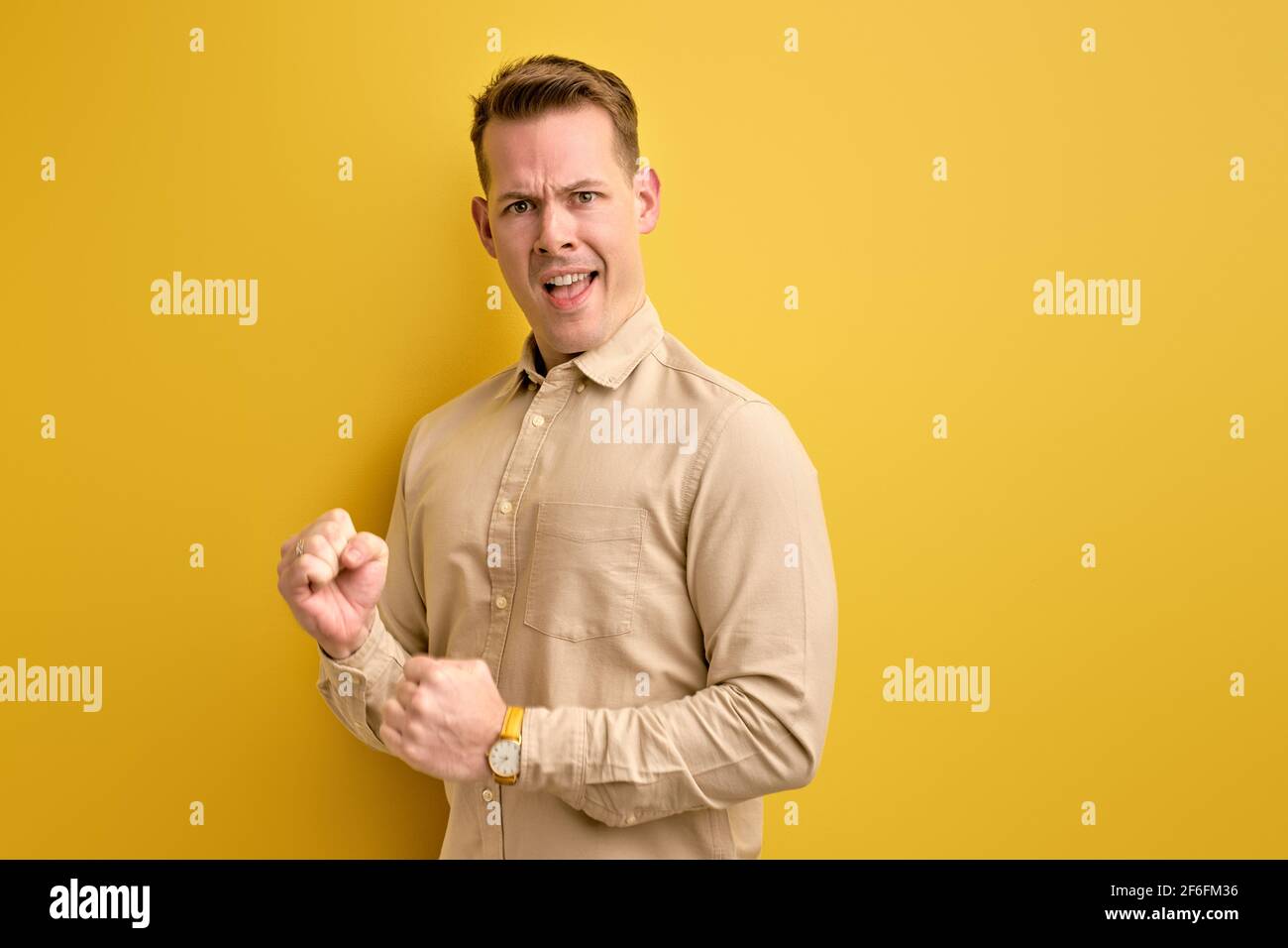 happy cheery guy showing winning gesture isolated on yellow studio ...