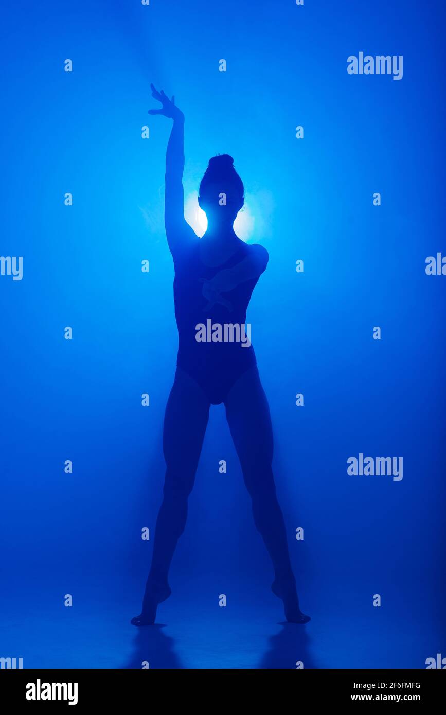 Ballerina in black bodysuit dancing with magic blue light and smoke ...