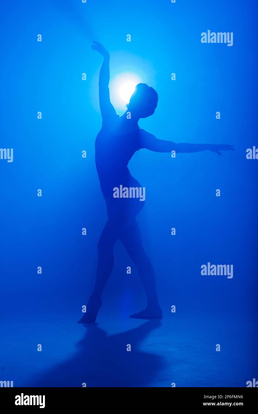 Ballerina in black bodysuit dancing with magic blue light and smoke ...