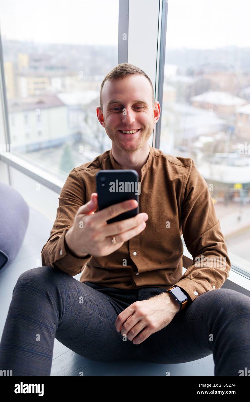 Handsome young male manager is sitting on the floor with the phone near ...