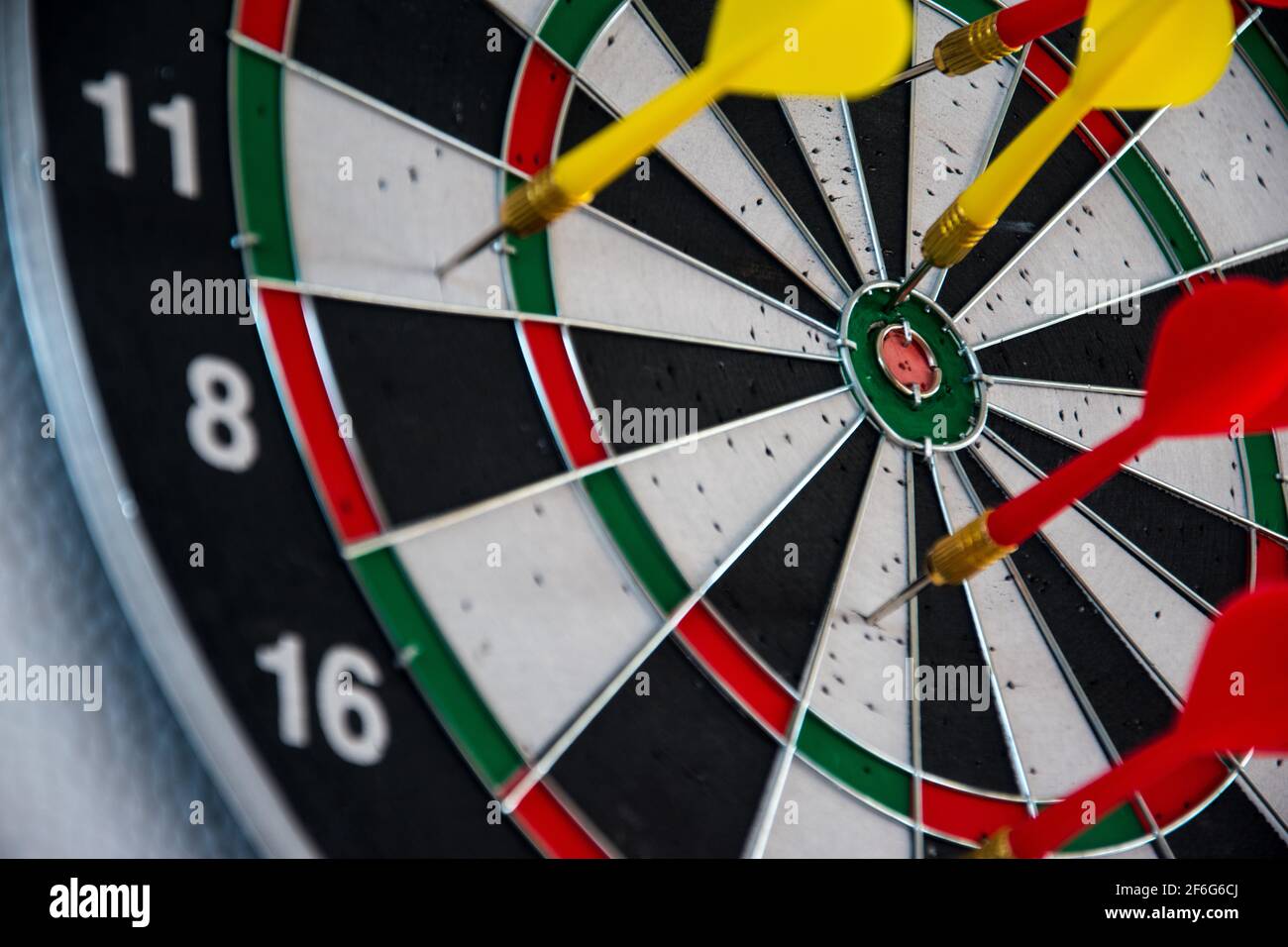 Datboard and some colorful darts used for lessure time on a white table ...