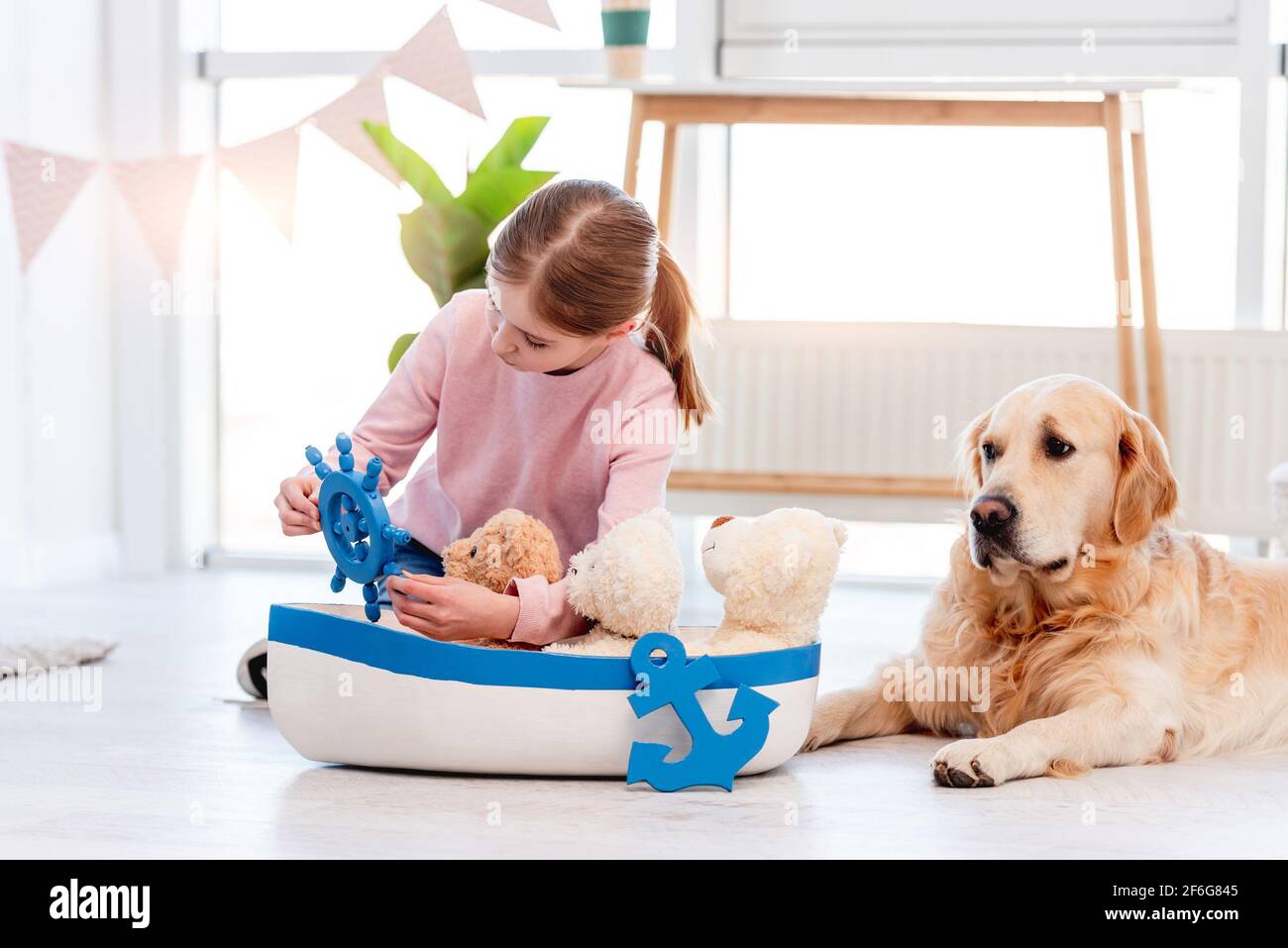 Little girl play with sea ship with golden retriever dog Stock Photo ...