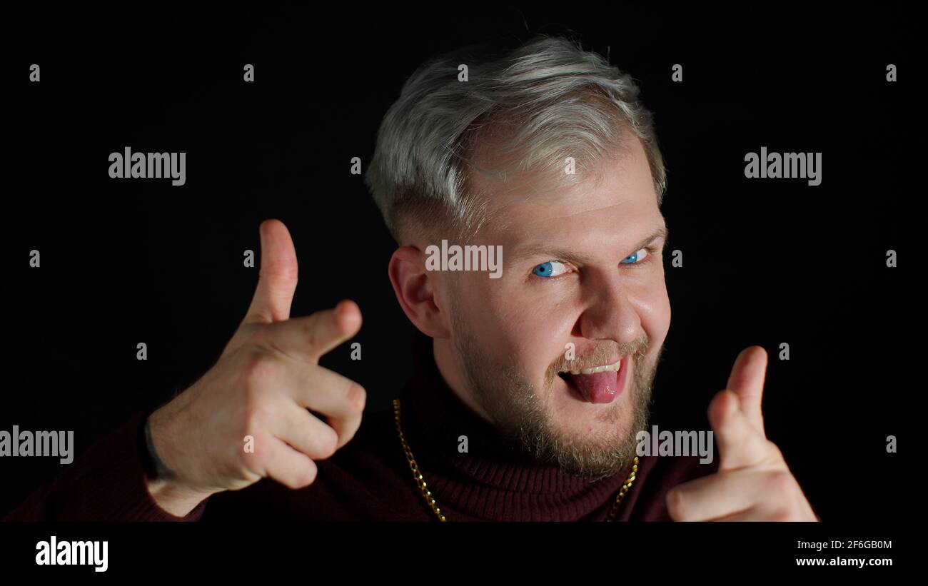 Happy stylish young man smiling excitedly and pointing to camera ...