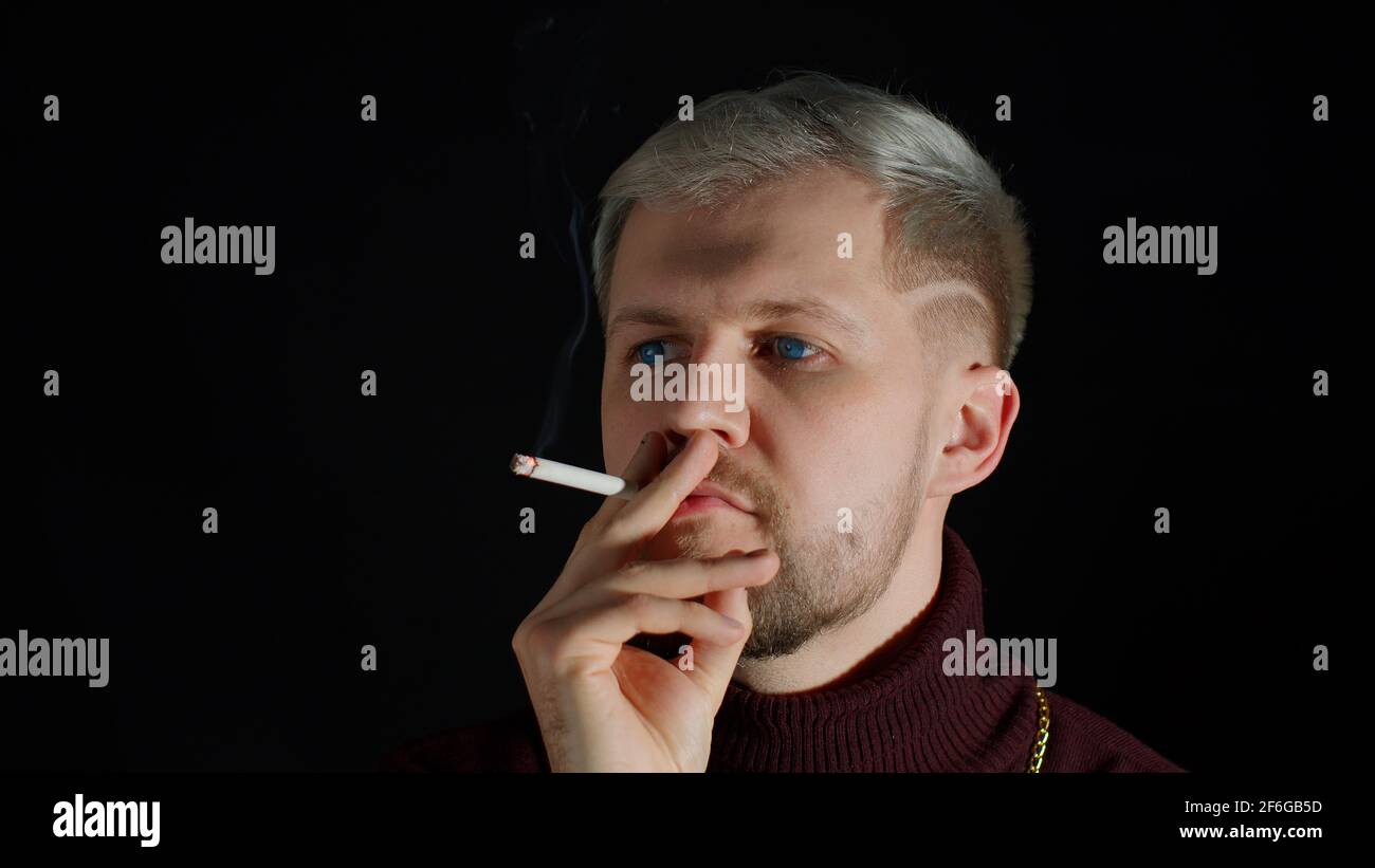 Stylish addicted young man with blue eyes in trendy clothes looking at ...