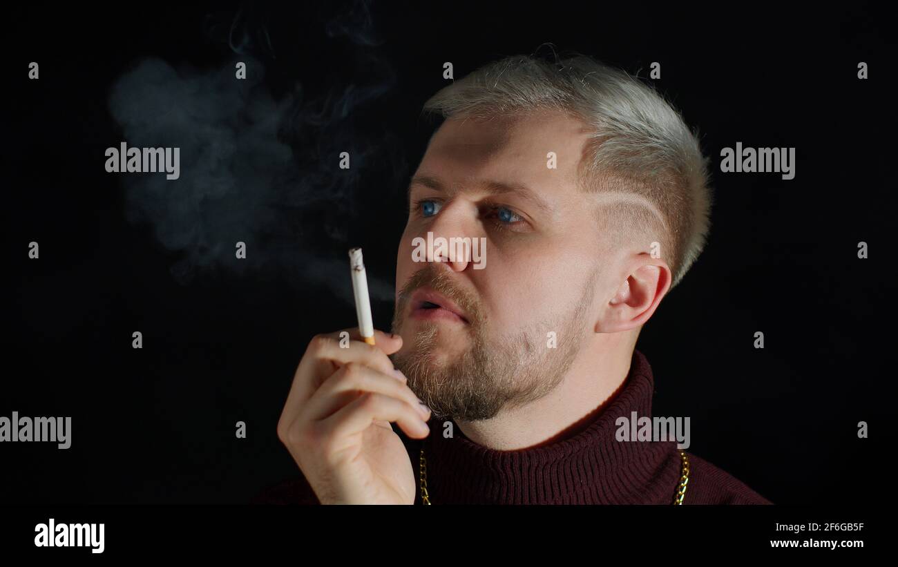 Stylish addicted young man with blue eyes in trendy clothes looking at ...
