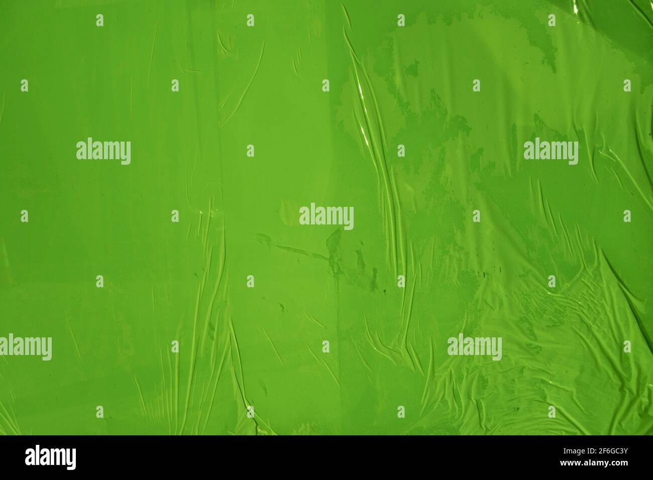Uneven green platic on flat surface with lines of air pockets and folds ...