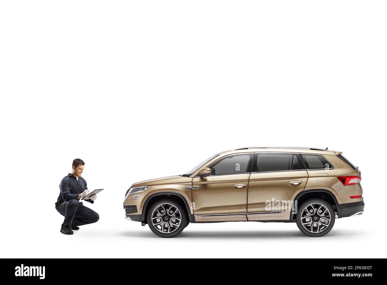 Auto mechanic kneeling and checking a SUV isolated on white background ...